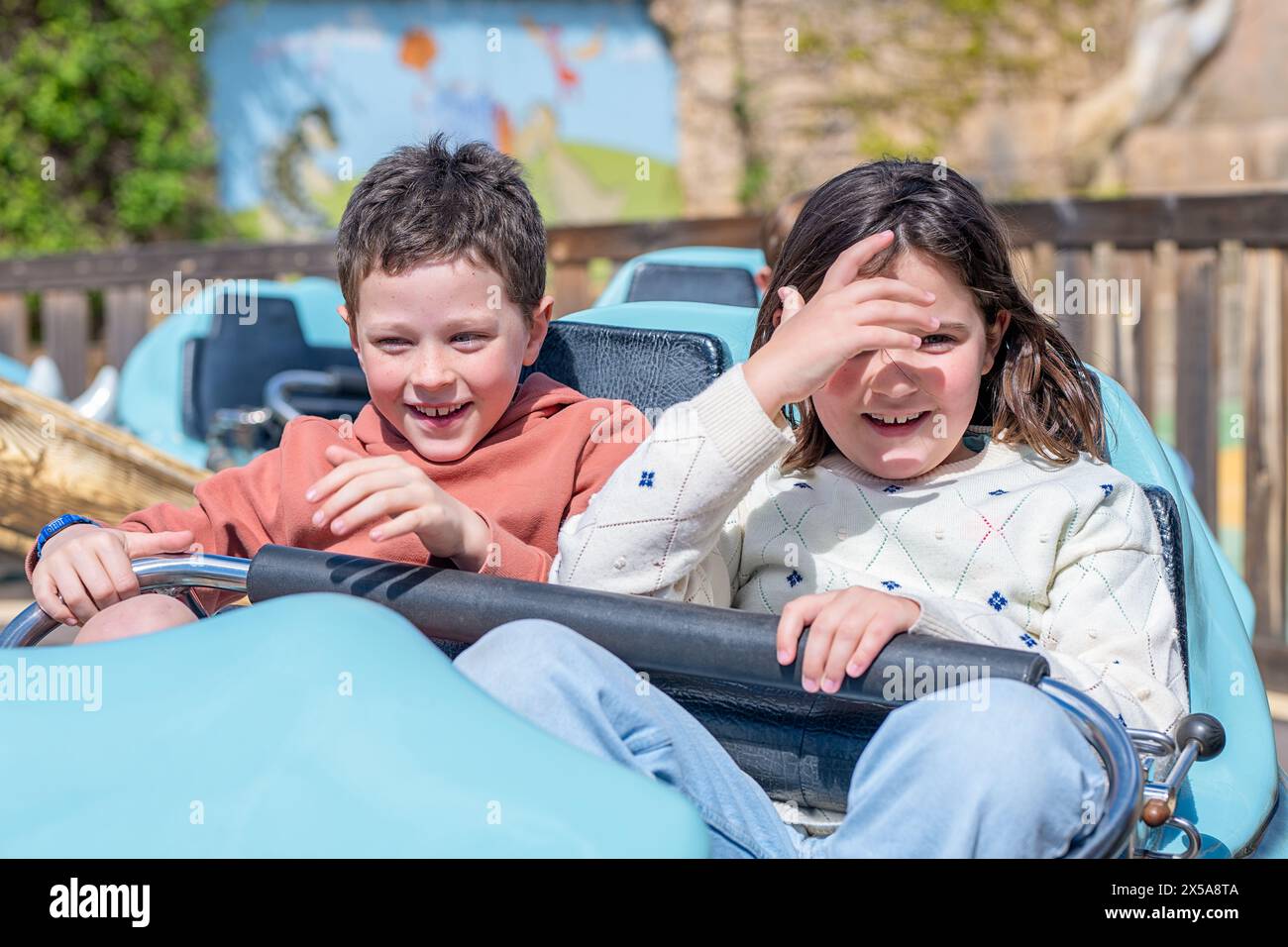 A boy and girl share a laugh on a summer amusement park ride, evoking ...