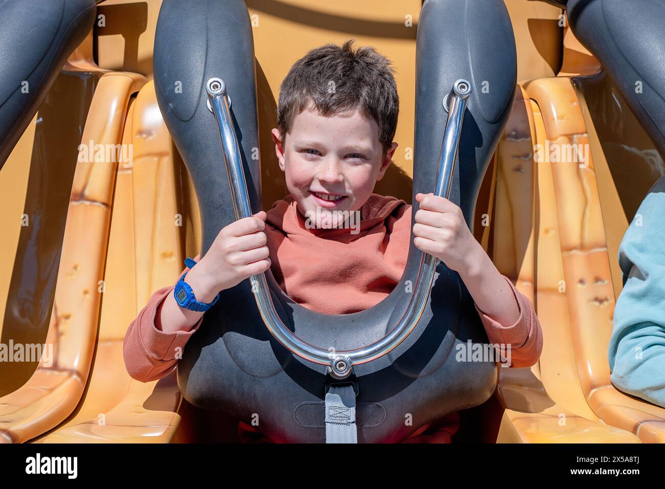 A happy boy with a giddy smile is seated and strapped in, ready for an ...
