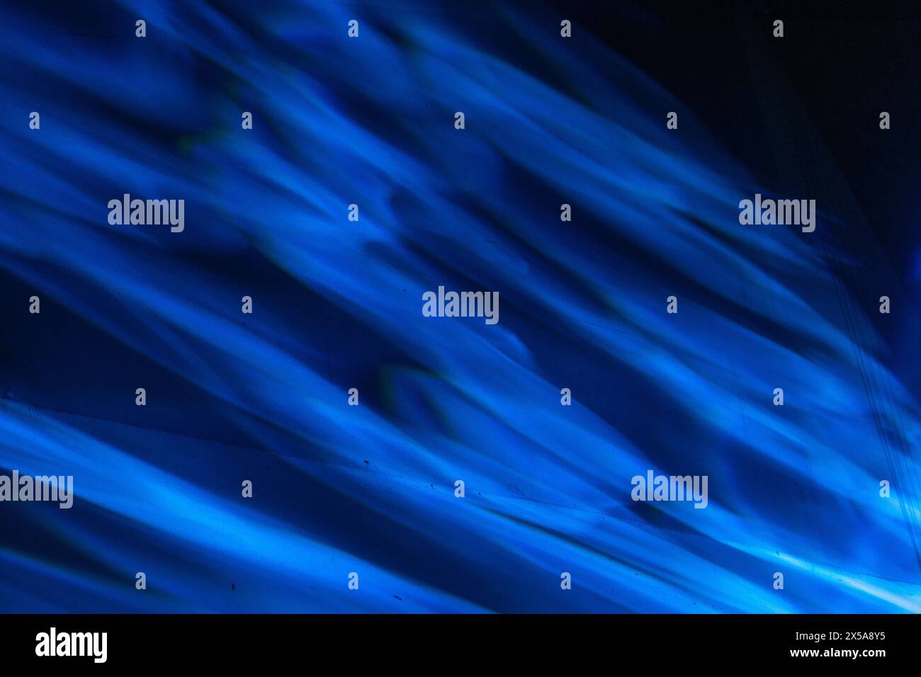 Dynamic blue light rays streak across a dark backdrop in an abstract ...