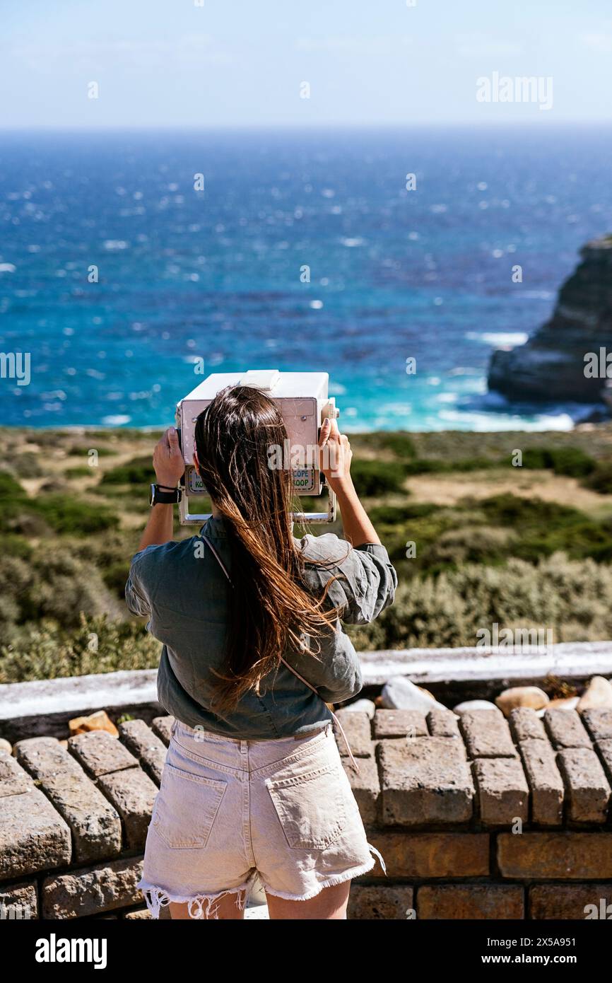 Back view of unrecognizable female tourist is seen using a coin ...