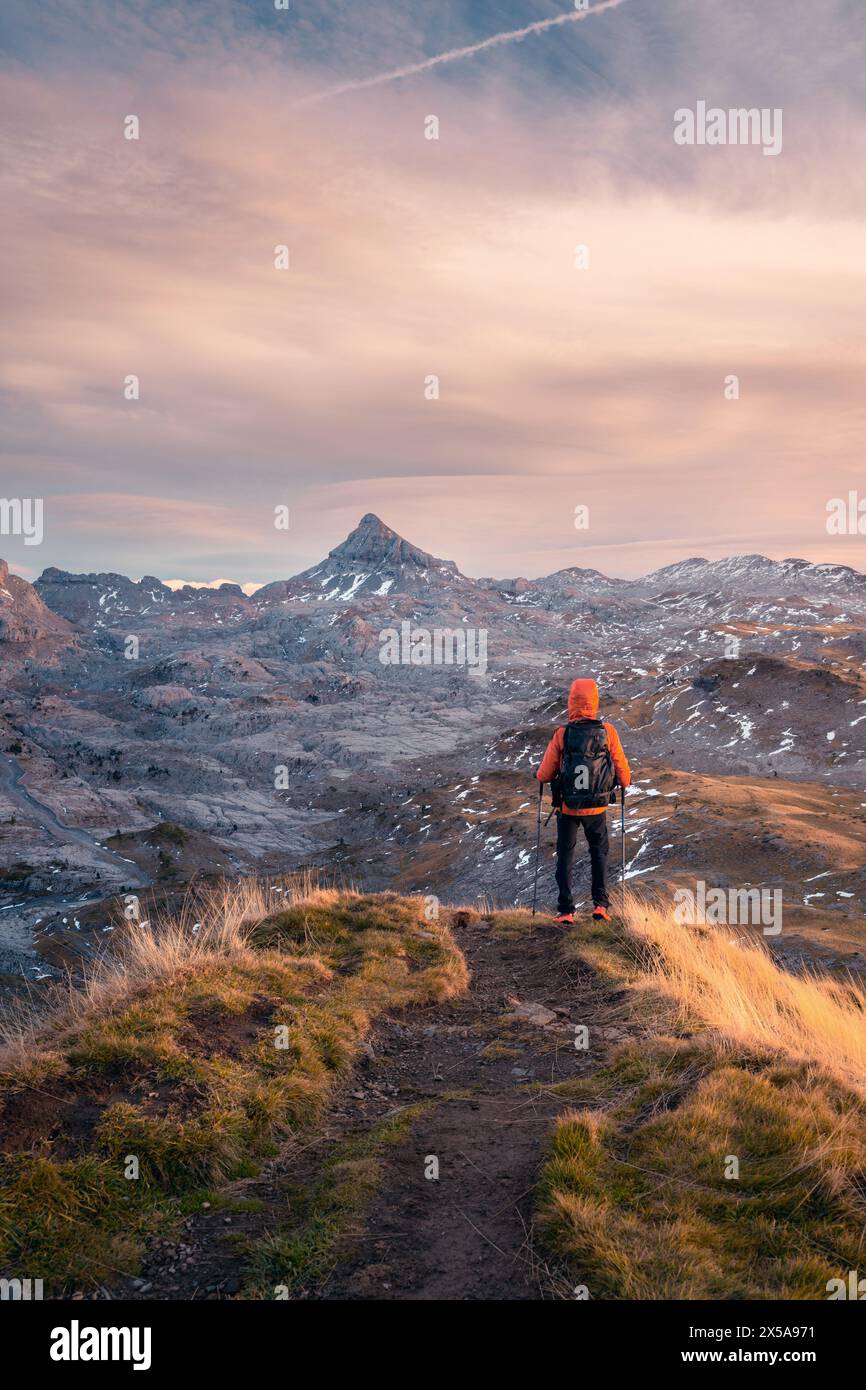 Back view of unrecognizable trekker stands captivated by the majestic ...