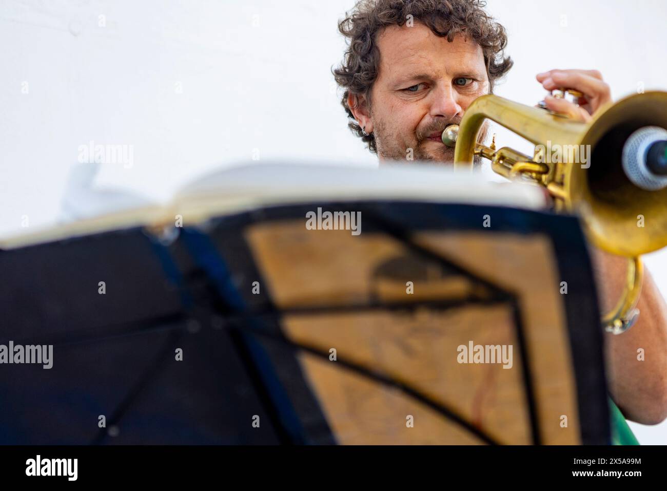 A man with one arm skillfully plays the trumpet on the street, focusing ...
