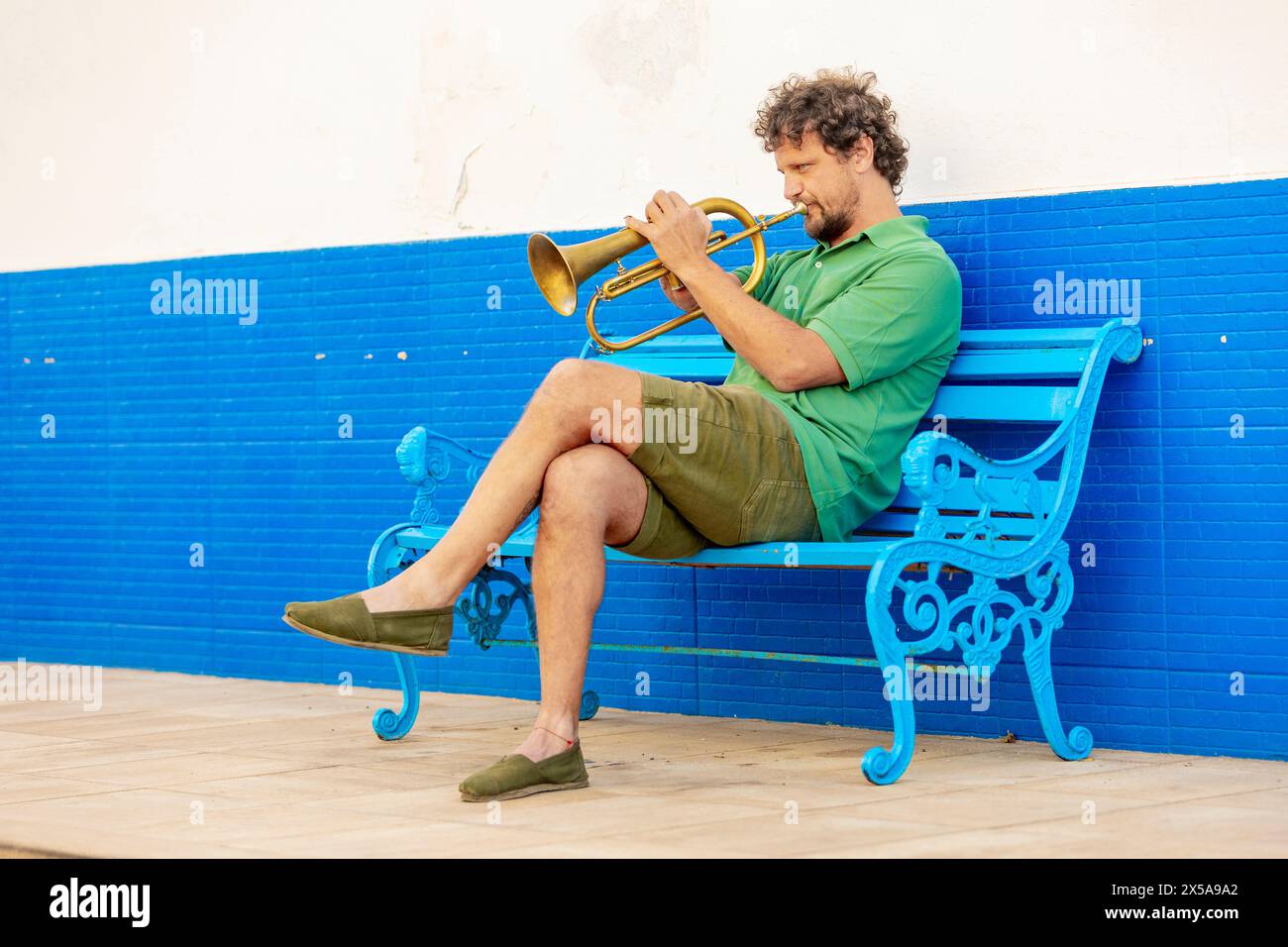 A one-armed man is deeply immersed in playing a trumpet while sitting ...