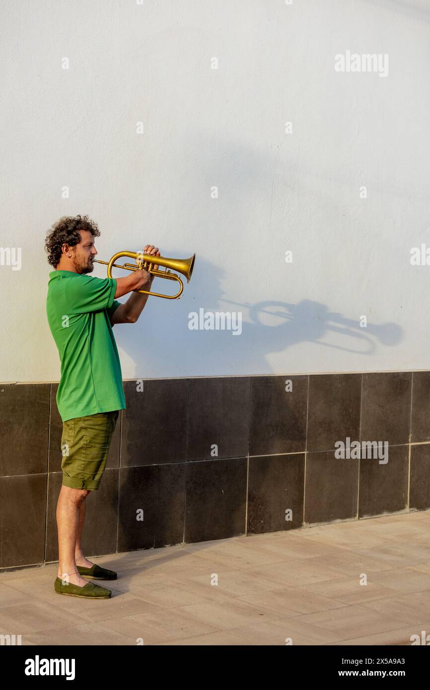 Side view of a resilient one-armed man plays the trumpet with passion ...