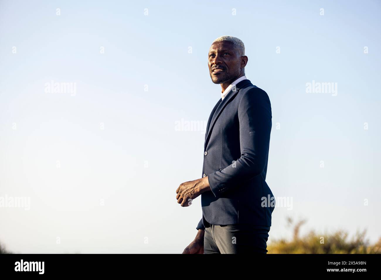 An elegant African American male model in a suit posing on a beach ...