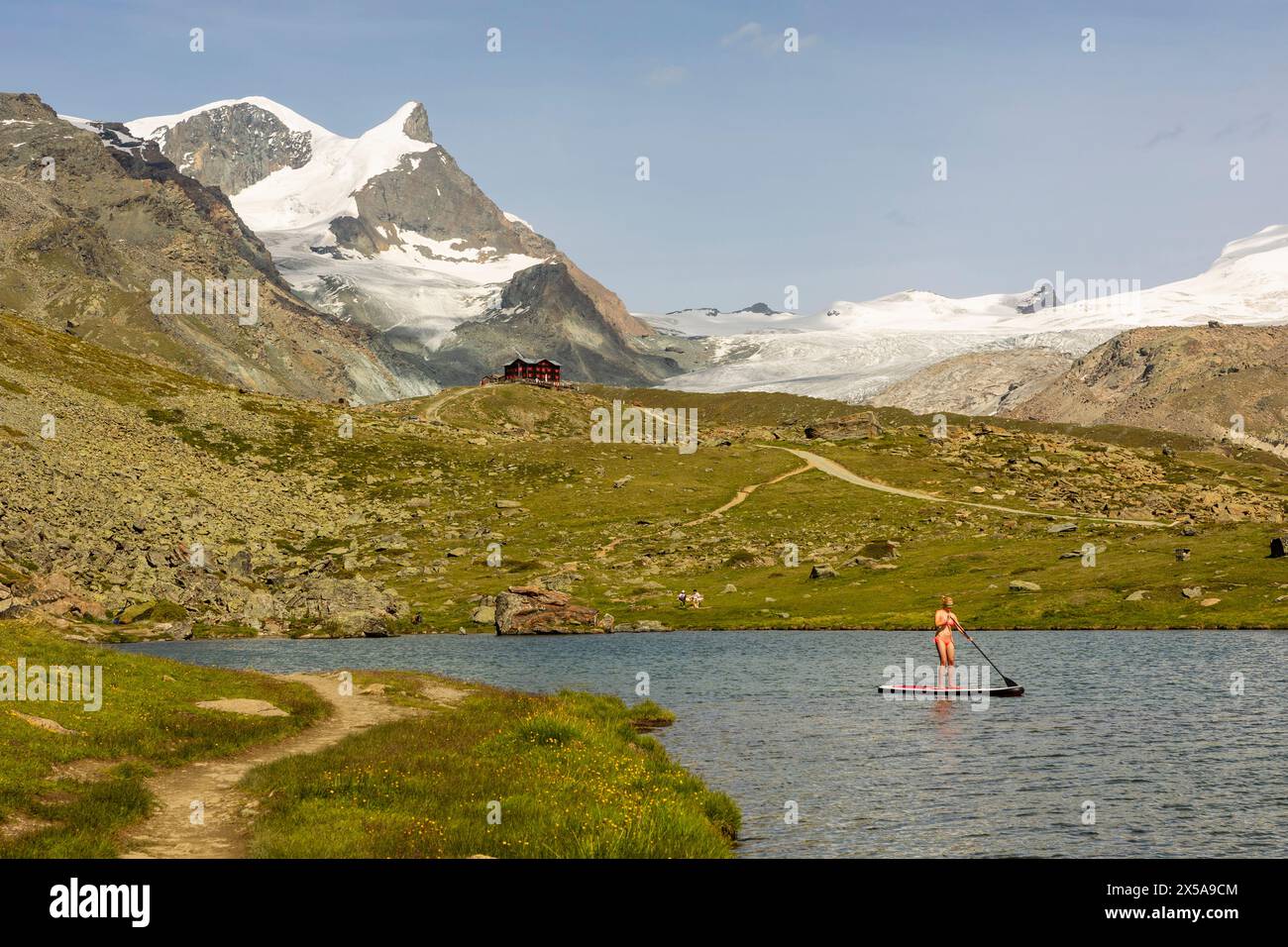 Person enjoying paddle surfing on a serene mountain lake with the ...