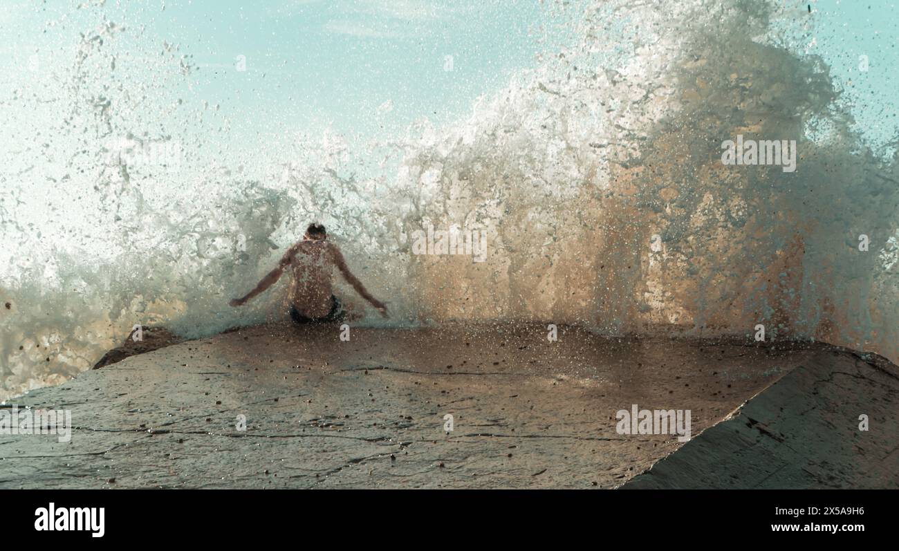 A person braced for impact as a majestic ocean wave crashes onto the ...