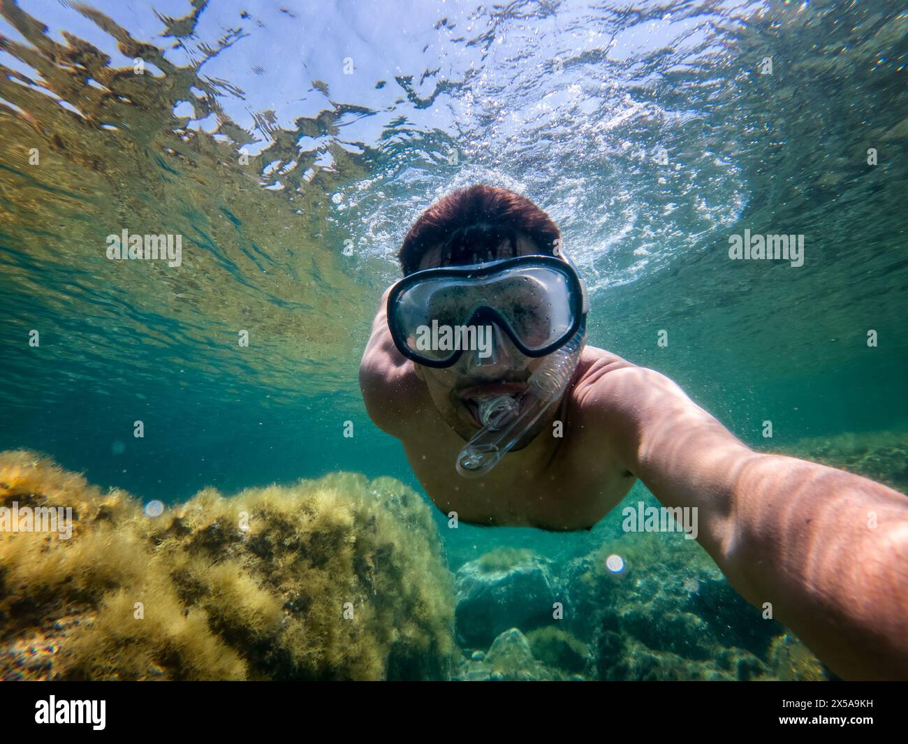 A snorkeler takes a selfie while exploring the clear underwater world ...