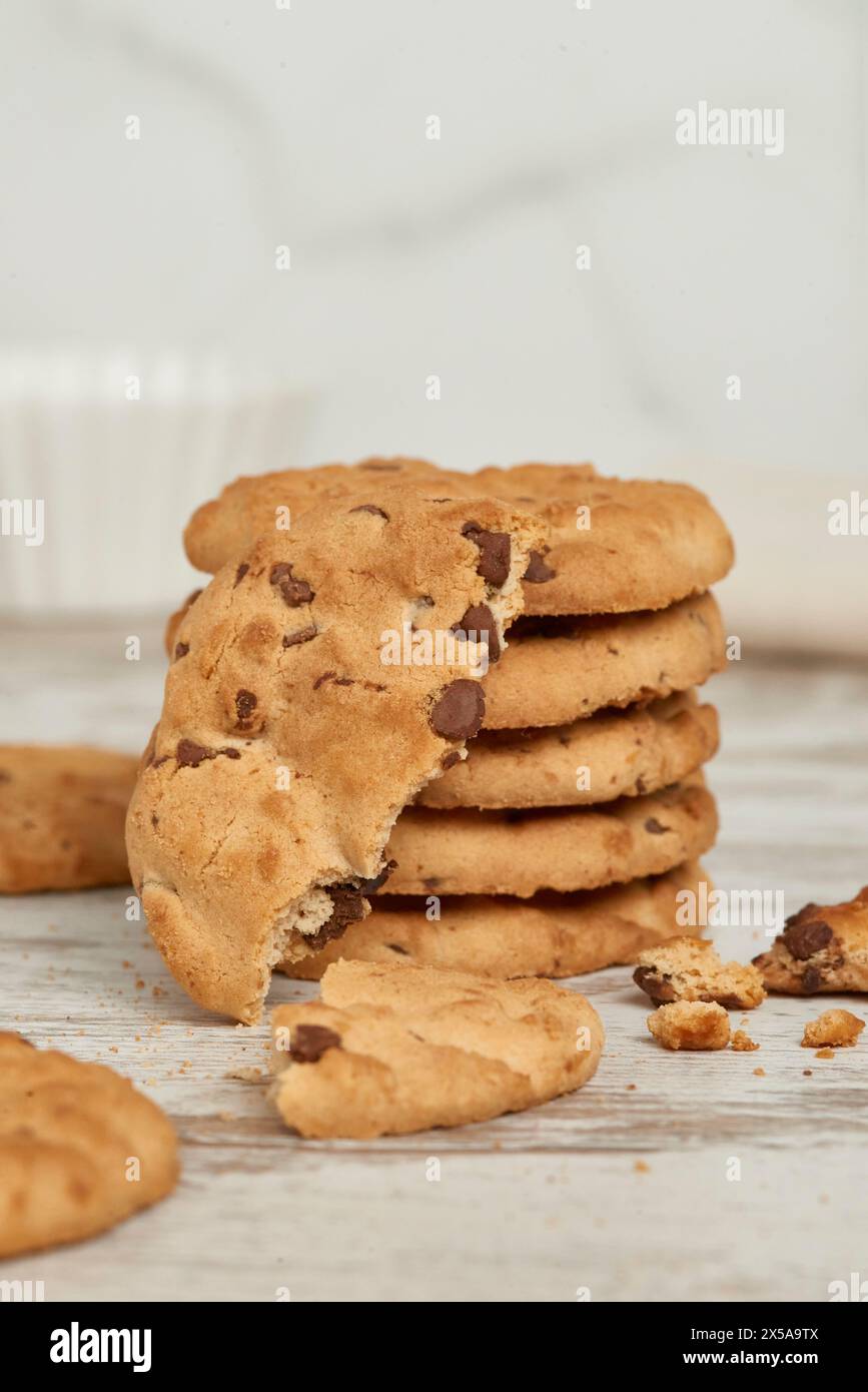 A delectable stack of chocolate chip cookies with crumbs scattered on a ...