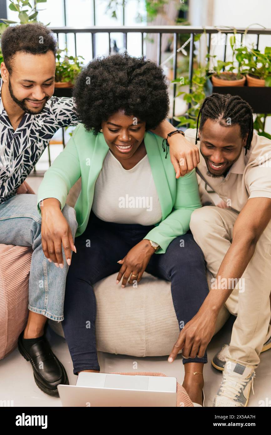 Three young professionals work together happily in a vibrant coworking ...