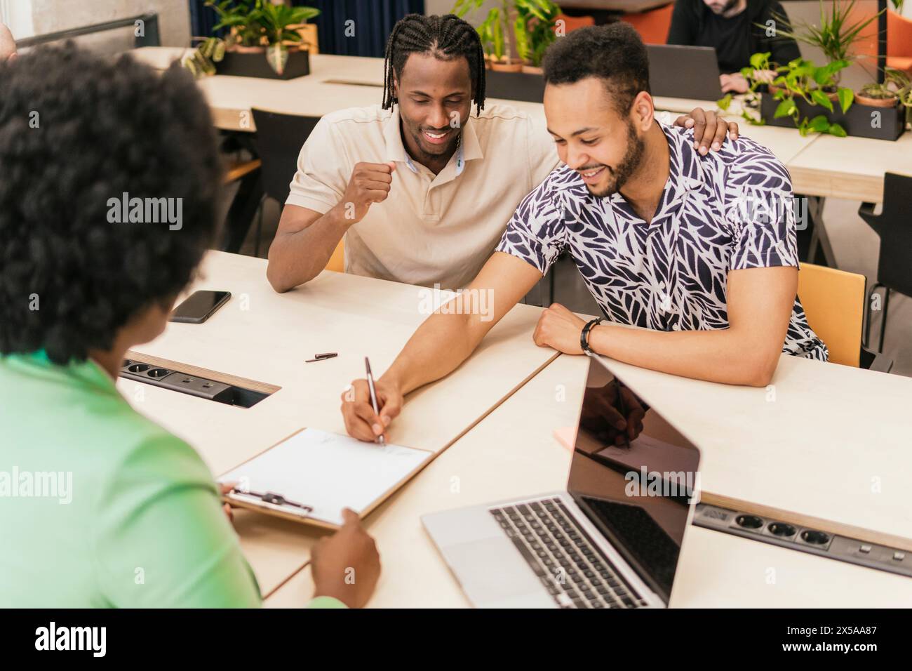 Three colleagues engage in a discussion at a well-lit coworking ...