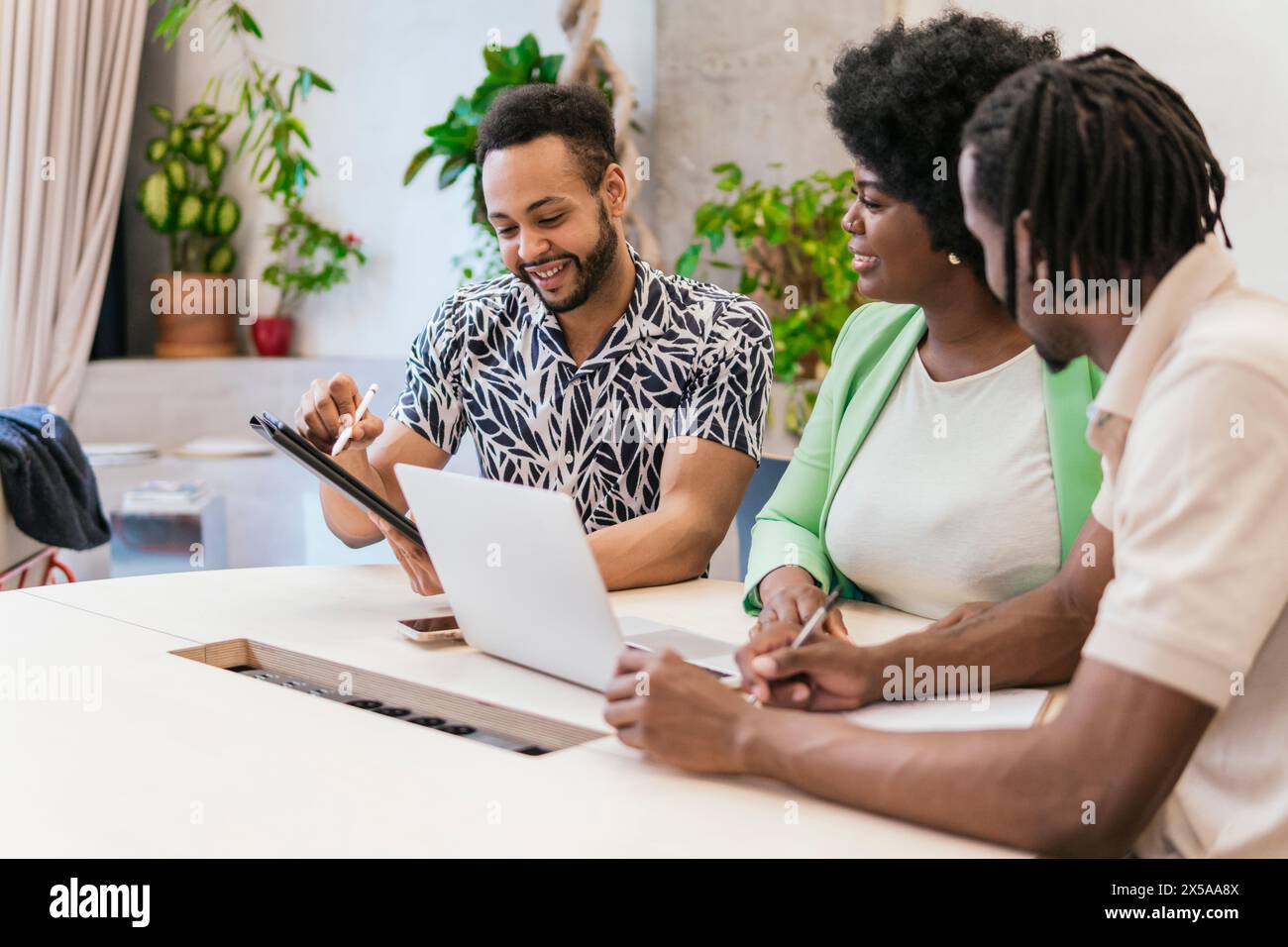 A diverse group of professionals collaborate in a bright, plant-filled ...