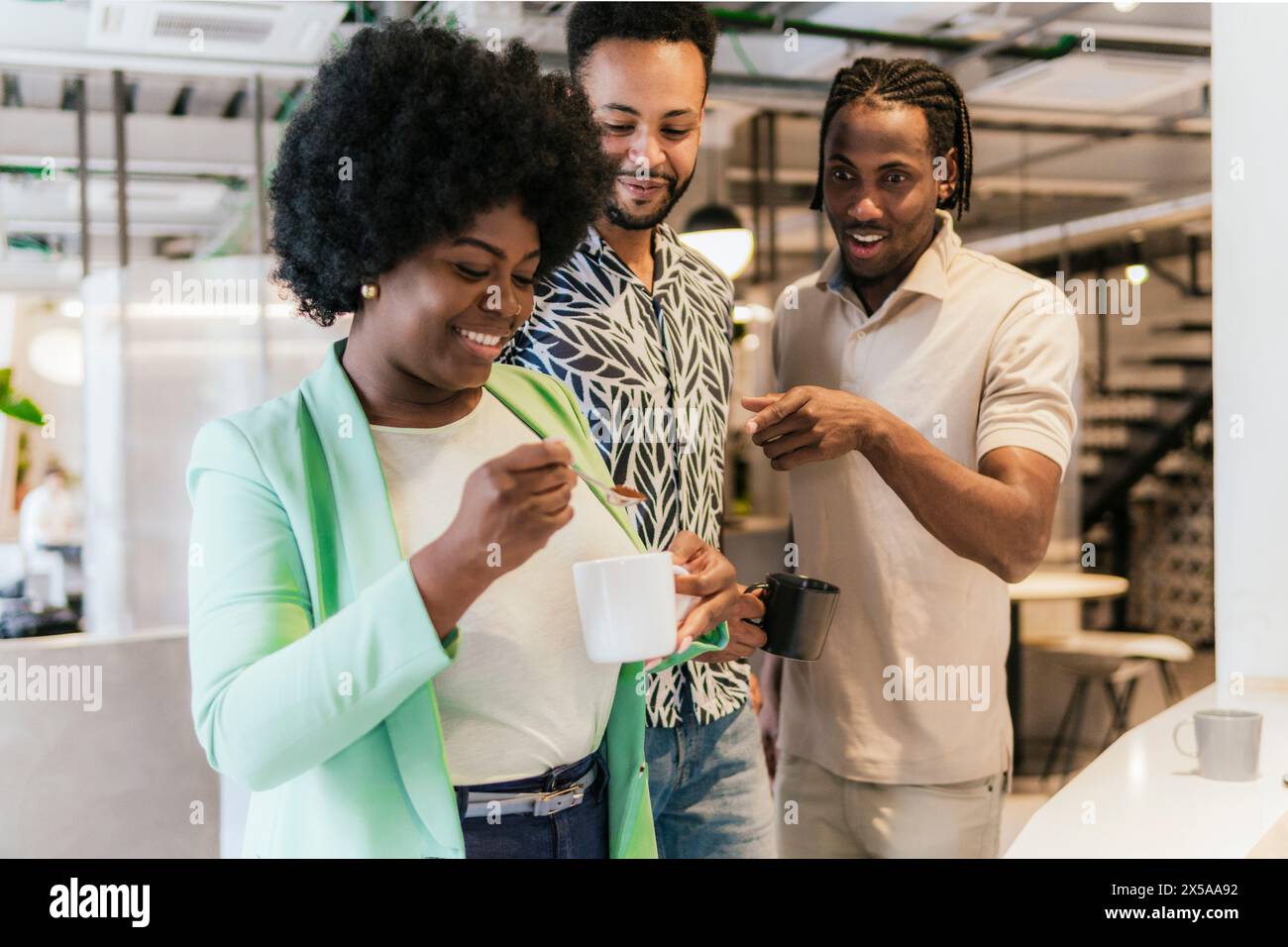 Three smiling colleagues engage in a light-hearted conversation over ...