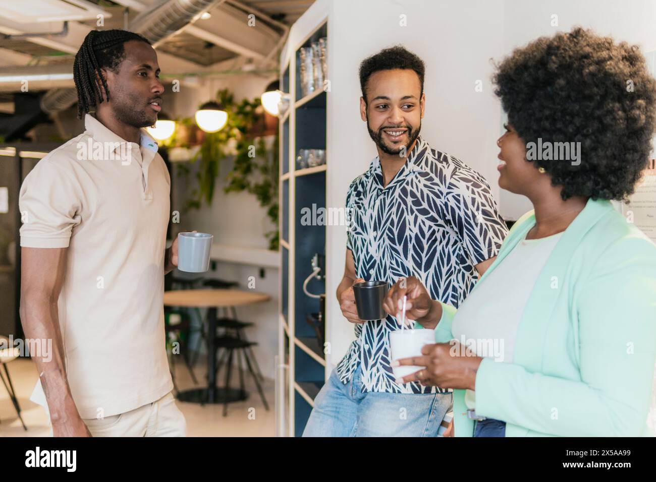 Three professionals engaging in a casual conversation in a modern ...