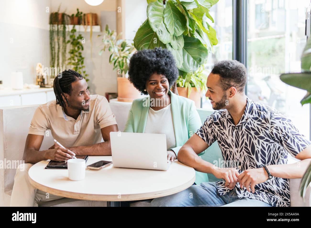 A diverse group of professionals engage in discussion around a laptop ...