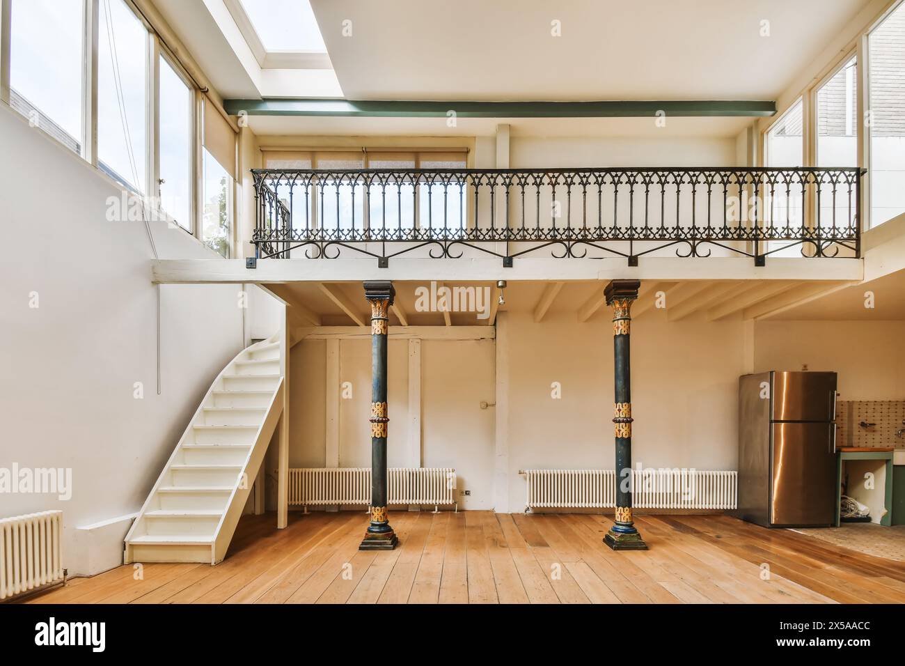 Loft space showcases an elegant black balcony railing, hardwood floors ...