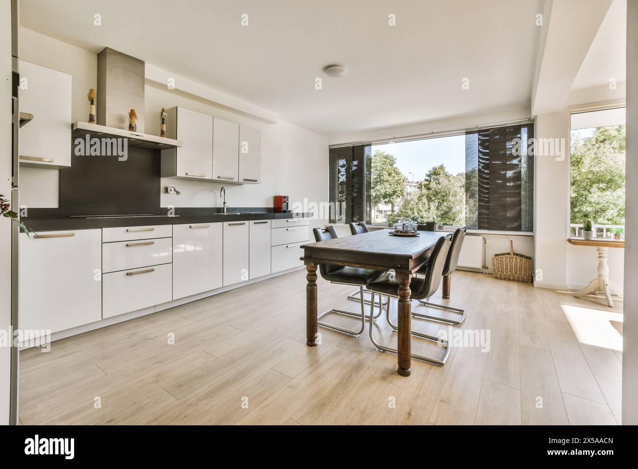A bright, spacious kitchen featuring white cabinetry, a dark countertop ...