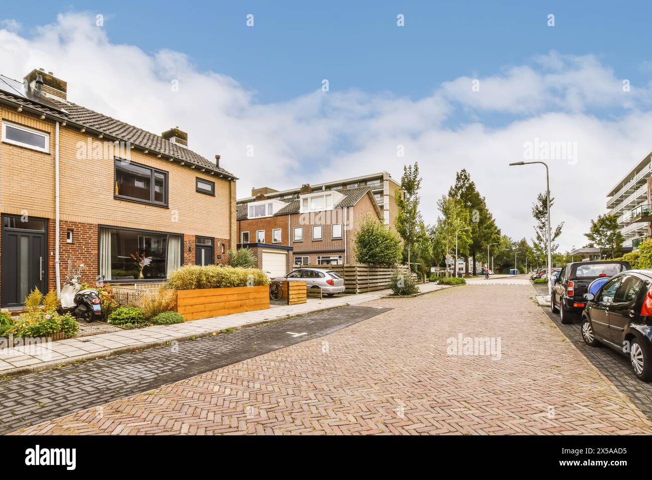A peaceful suburban street lined with detached and semi-detached houses ...