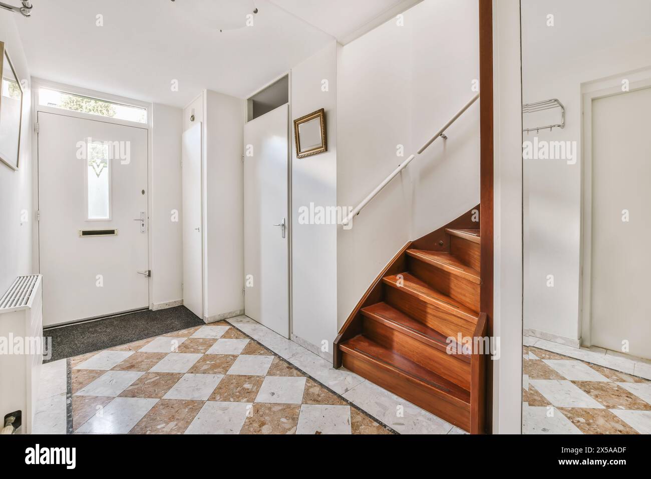 A clean, well-lit entryway features white walls, a staircase with ...