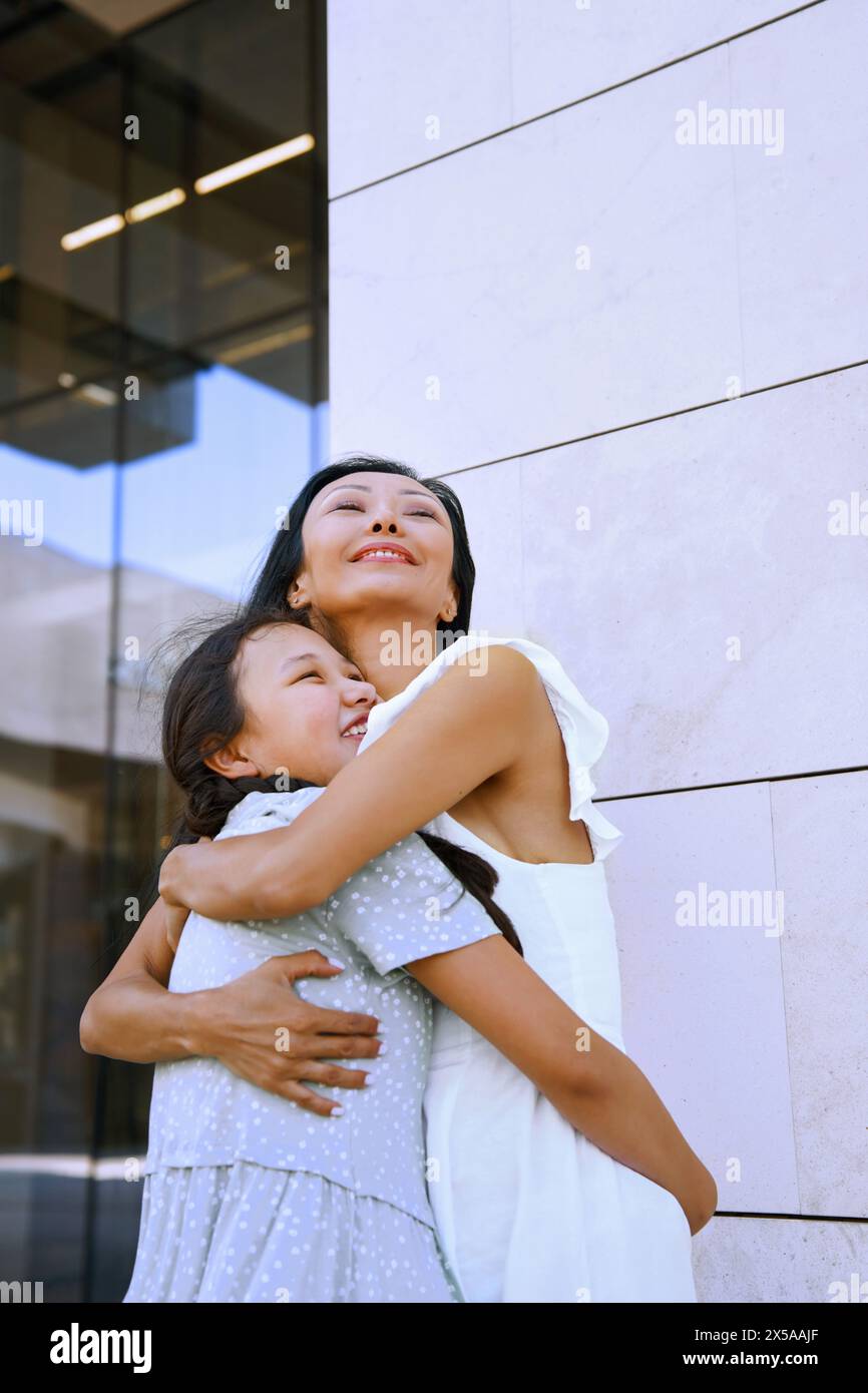 Girl with autism spectrum hugging her mother while walking in the city ...