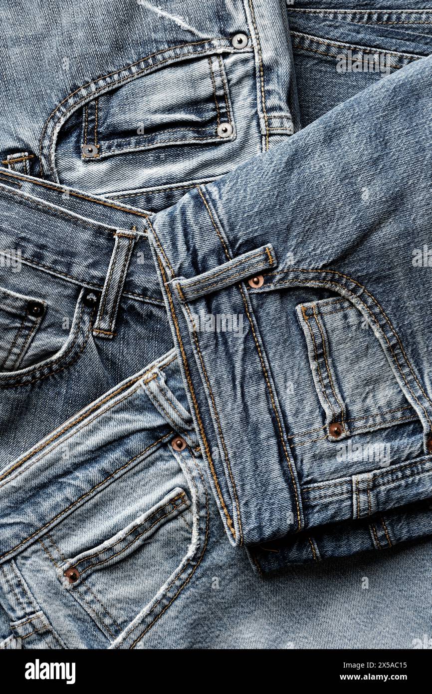 Group of aged denim jeans, arranged as abstract blue textile background ...