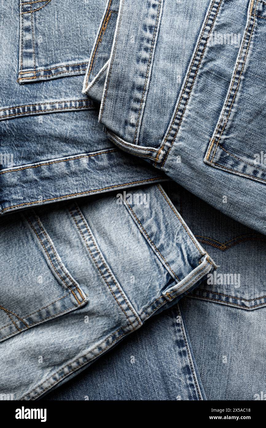 Group of aged denim jeans, arranged as abstract blue textile background ...