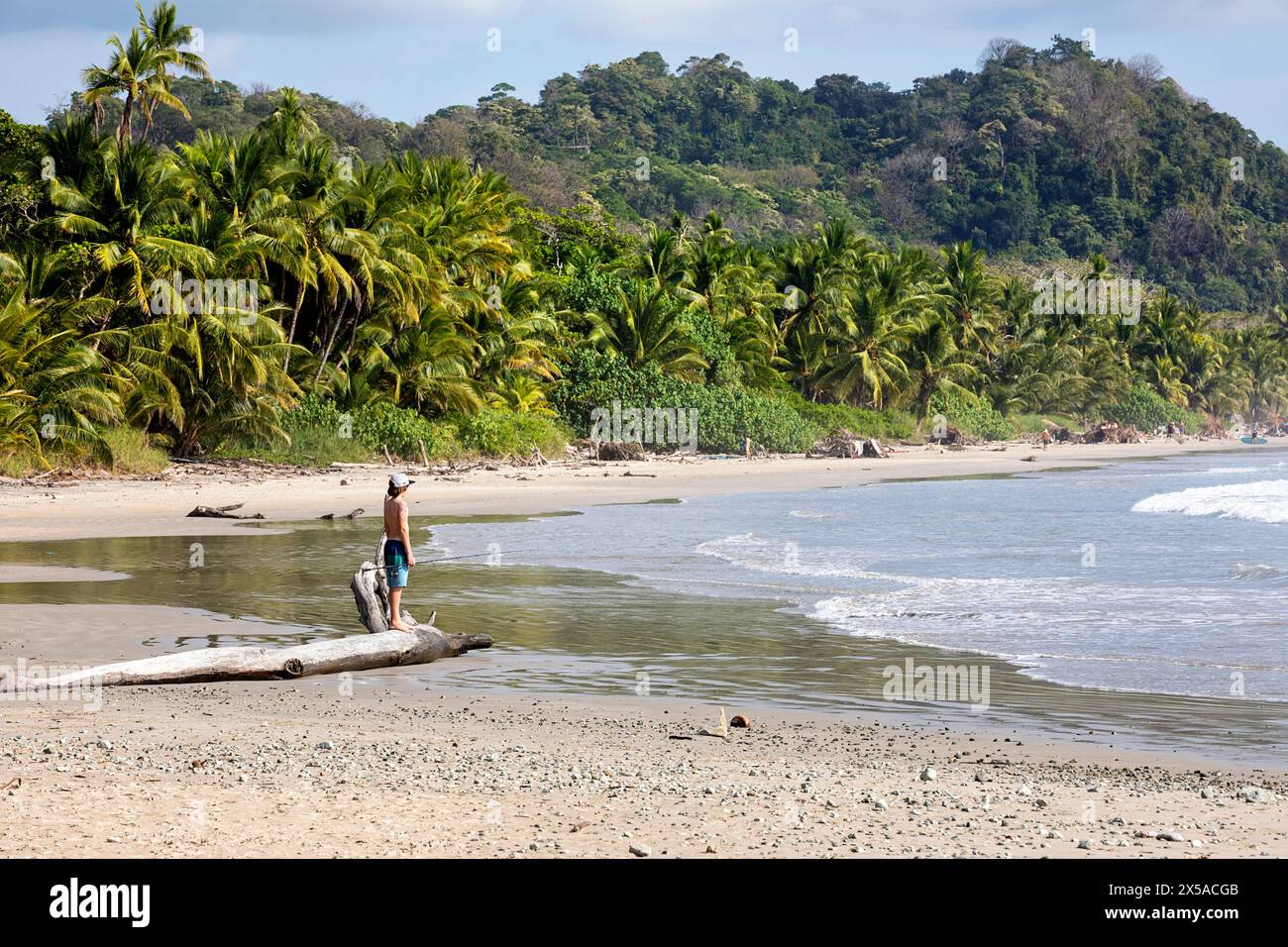 Kid, tourist with fishing rod on a Tree log on a Playa Hermosa, beach ...