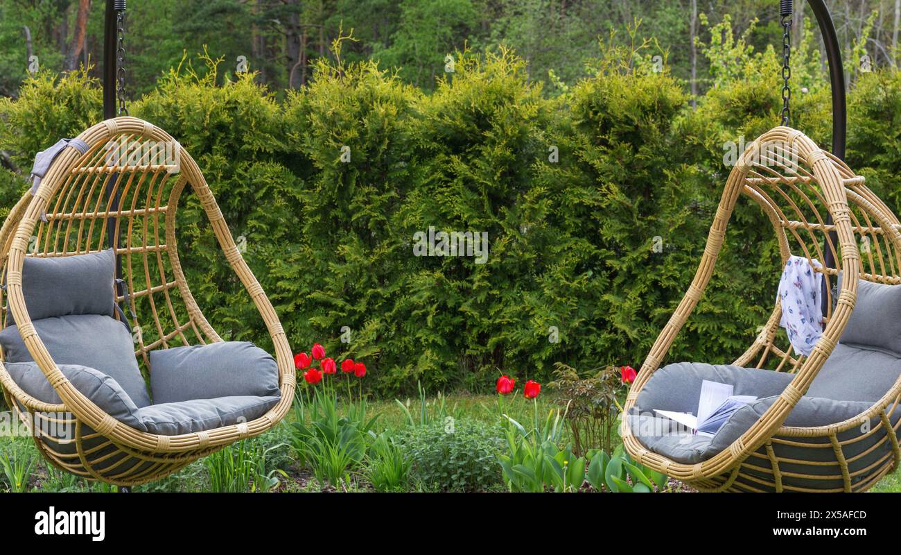 Rattan garden swing with cushion in the garden, seating area in the ...