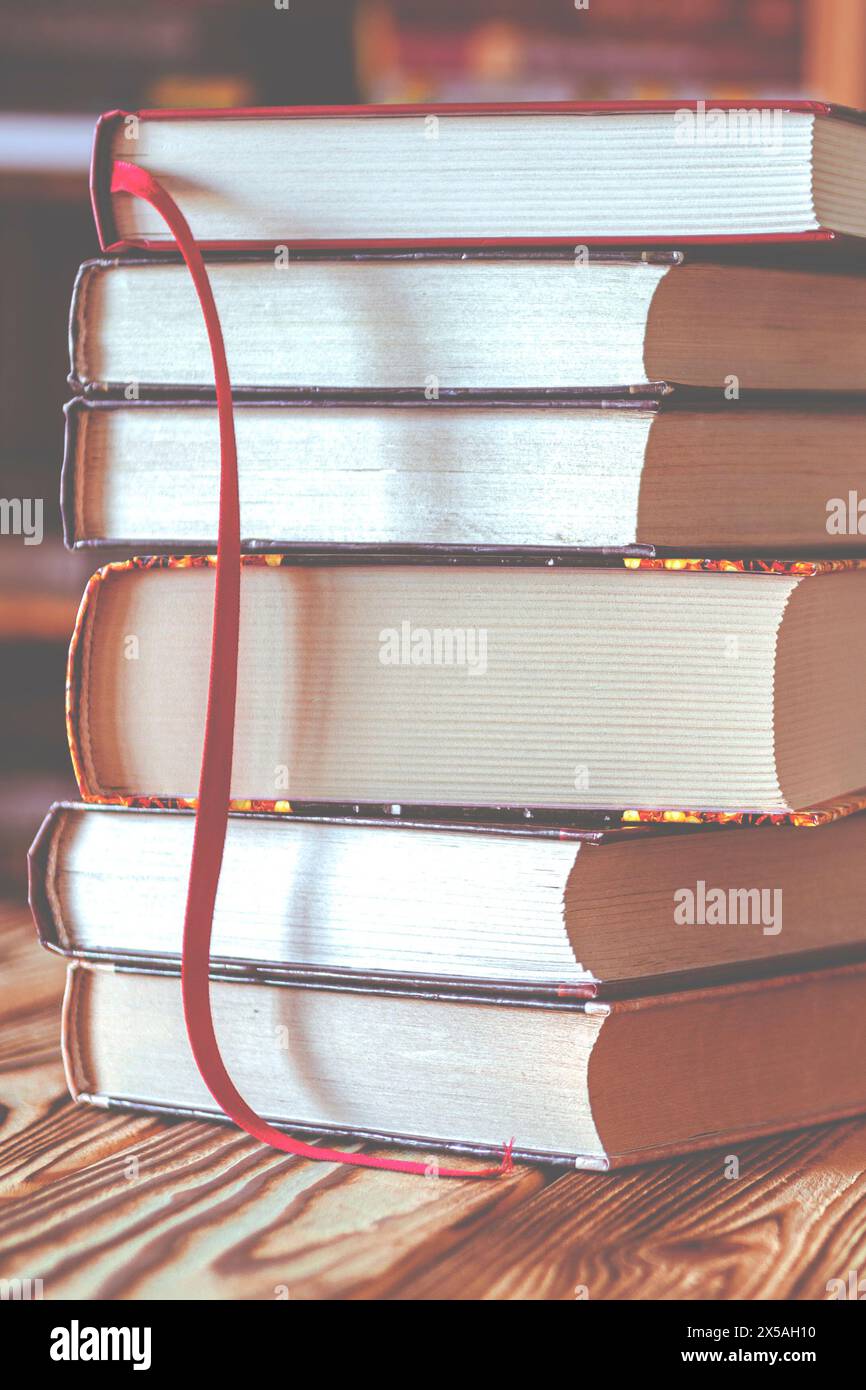 A stack of old books on table against background of bookshelf in ...