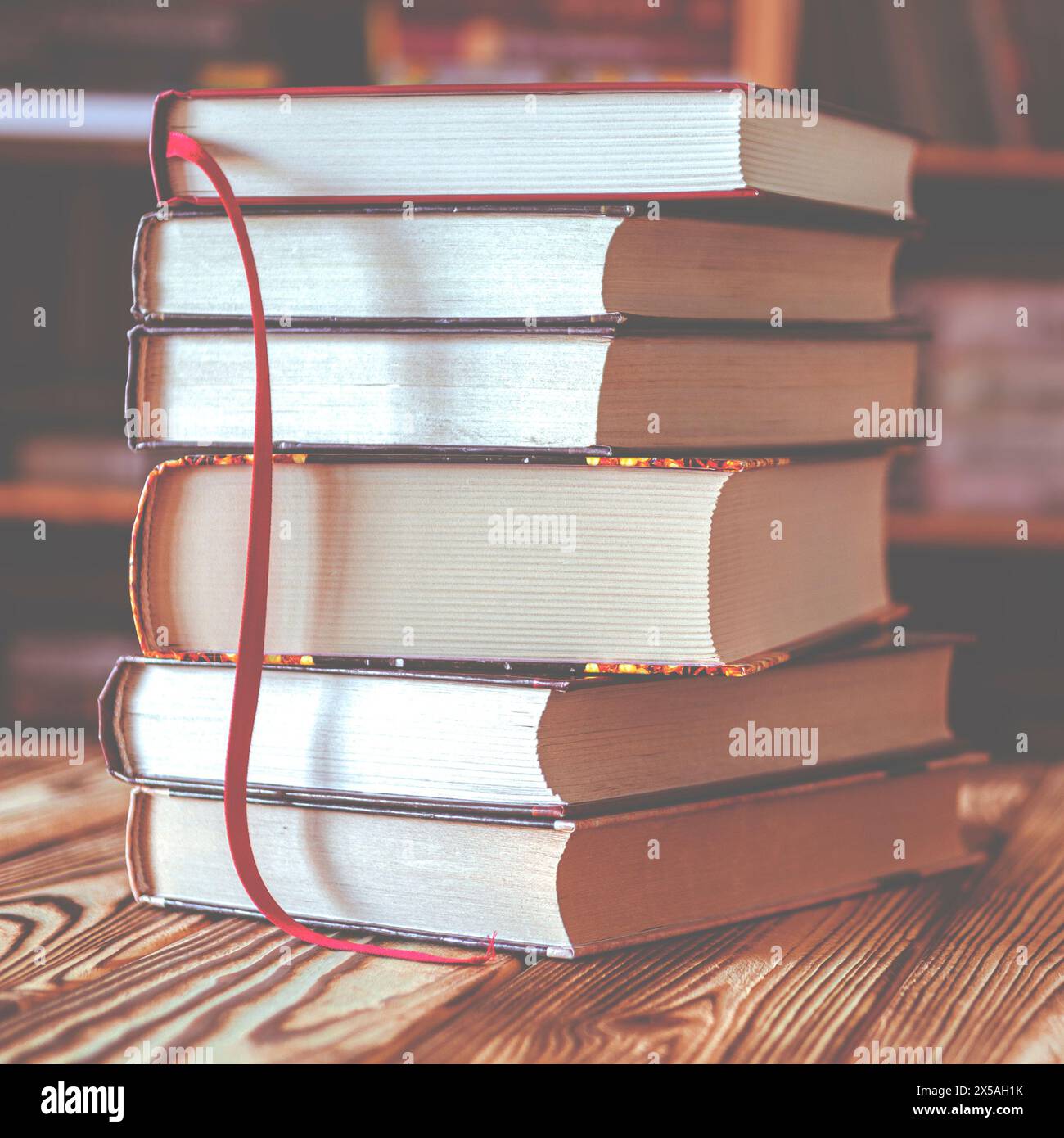 A stack of old books on table against background of bookshelf in ...