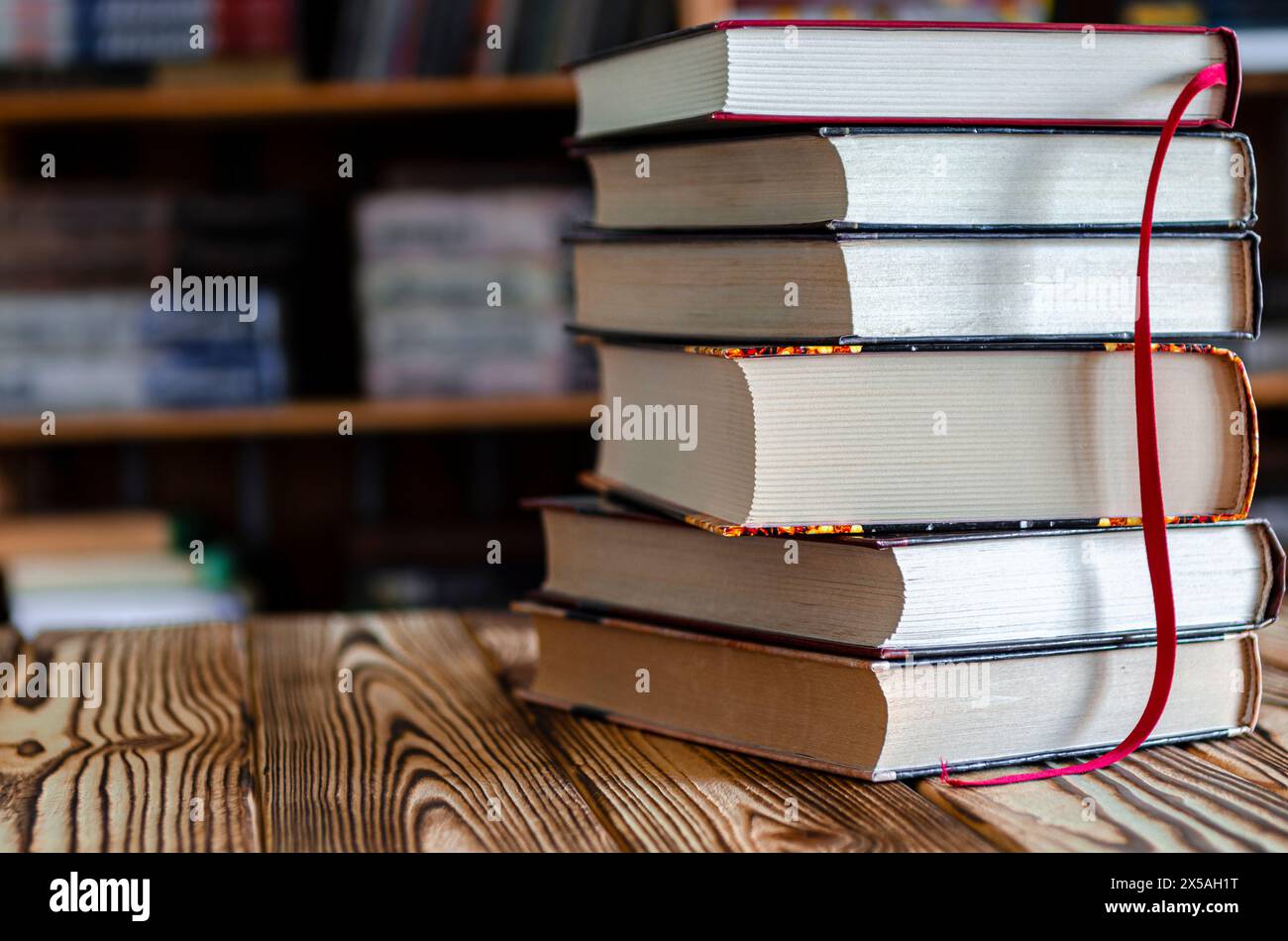 A stack of old books on table against background of bookshelf in ...