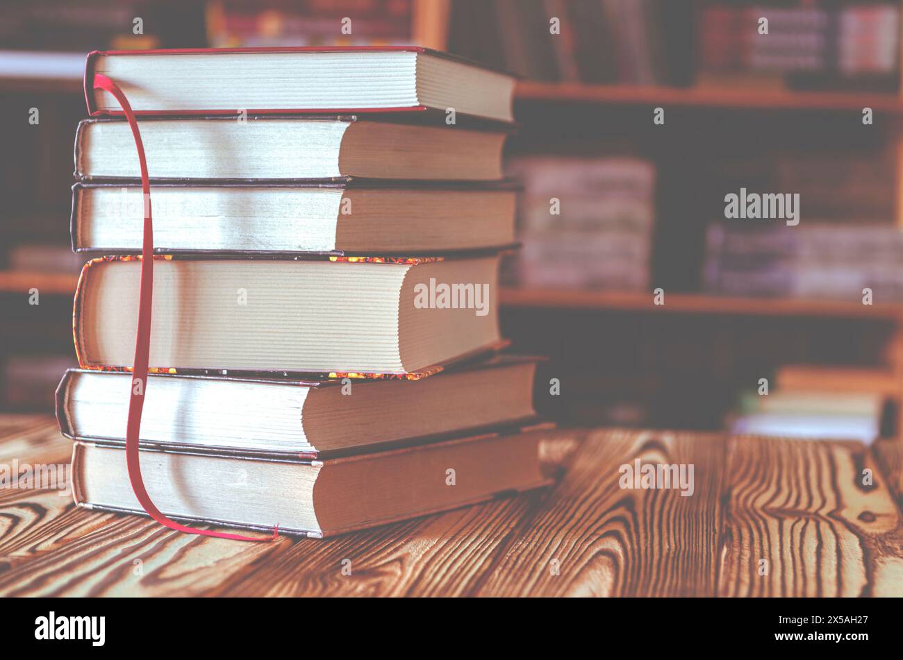 A stack of old books on table against background of bookshelf in ...