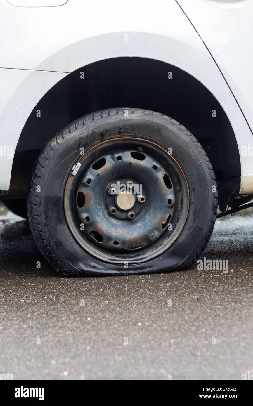 A car with a flat automotive tire on the side of the road, showing its ...