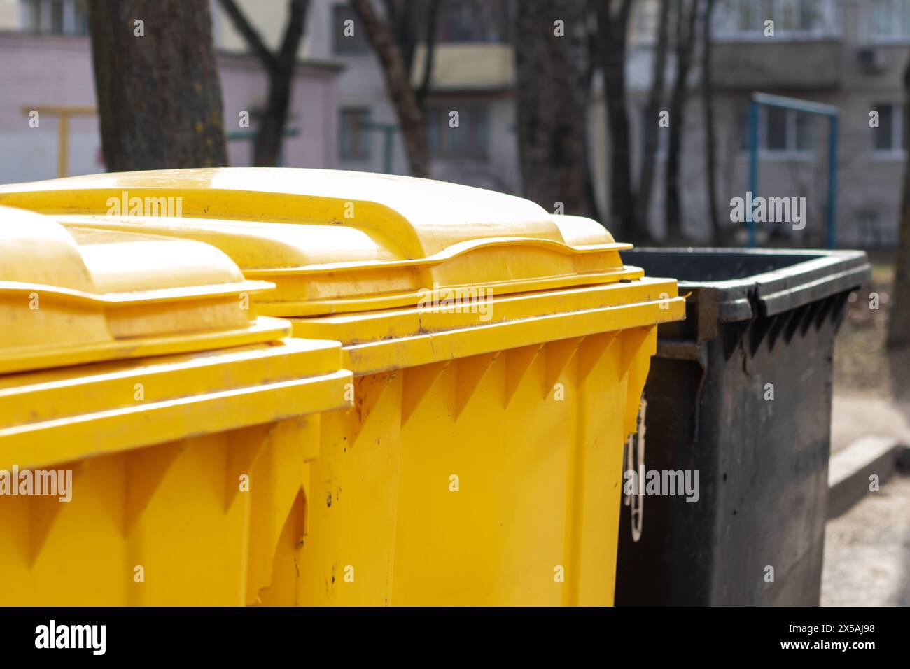 A yellow waste container made of composite material sits next to a ...