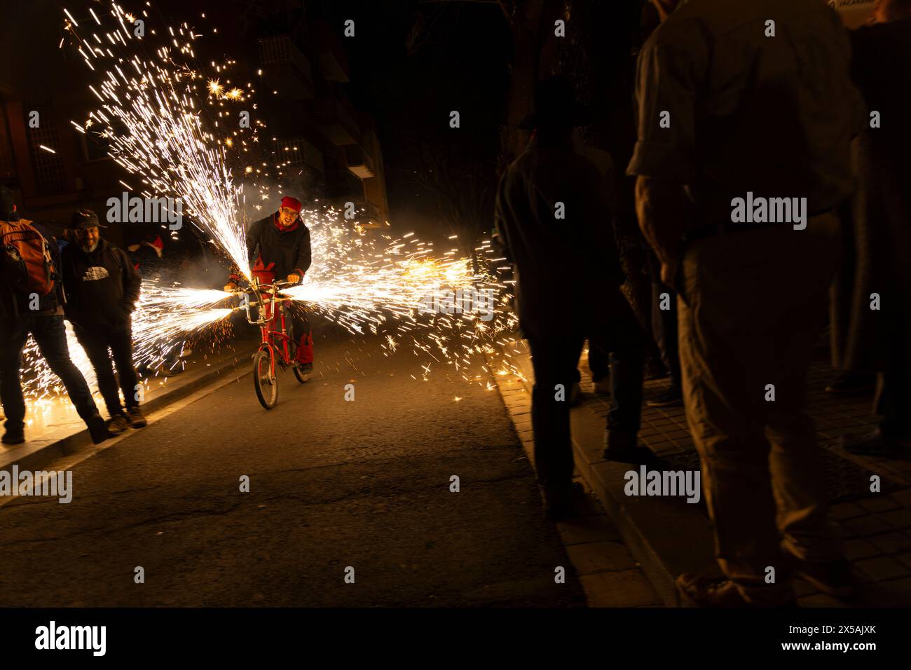 A Correfoc riding a bike loaded with fireworks Stock Photo - Alamy
