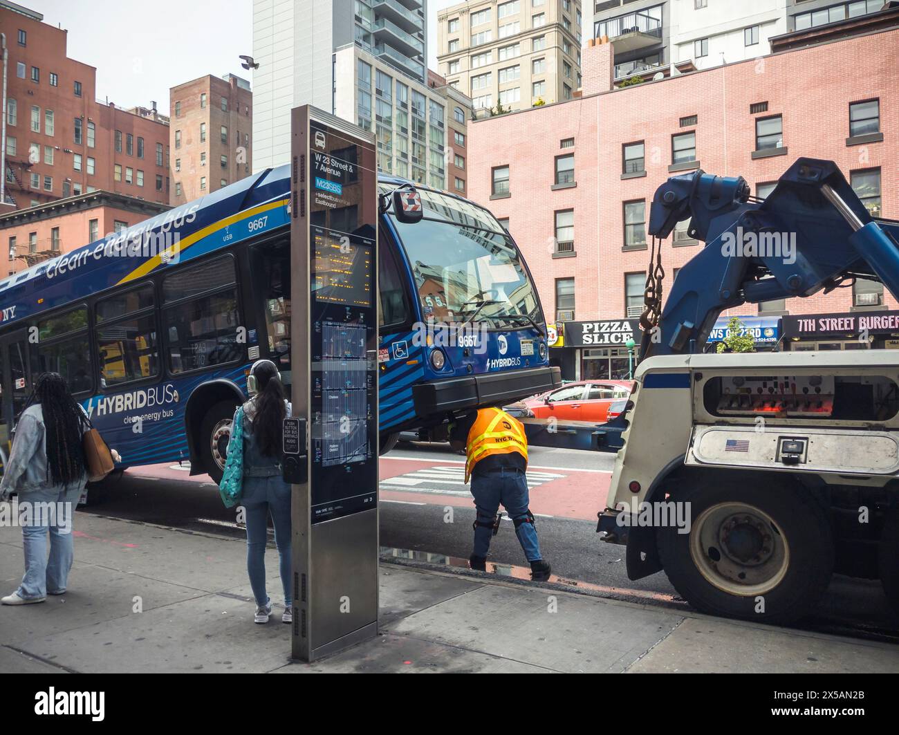 A worker prepares to tow a disabled NYCTA bus in Chelsea in New York on ...