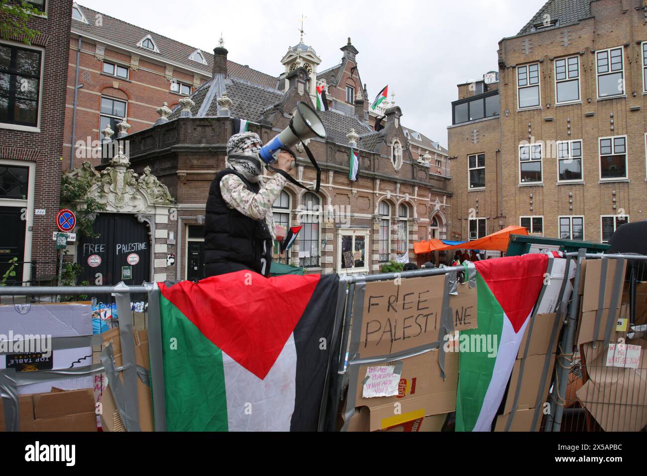Pro-Palestinian student speaks slogan on a megaphone up a barricade ...