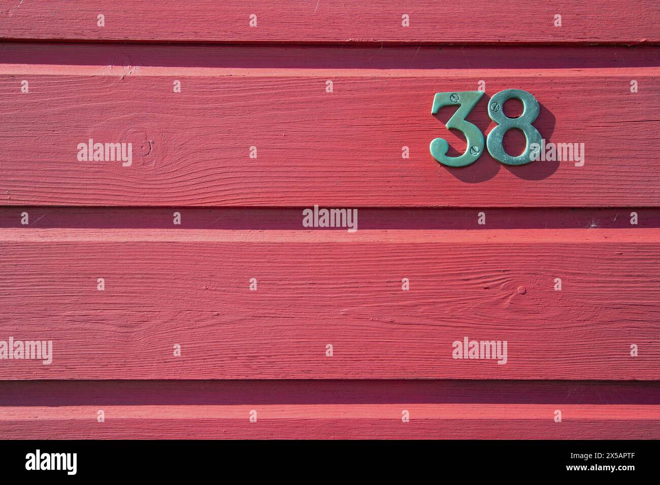 Close up shot of brass number 38 on red painted weatherboards of a ...
