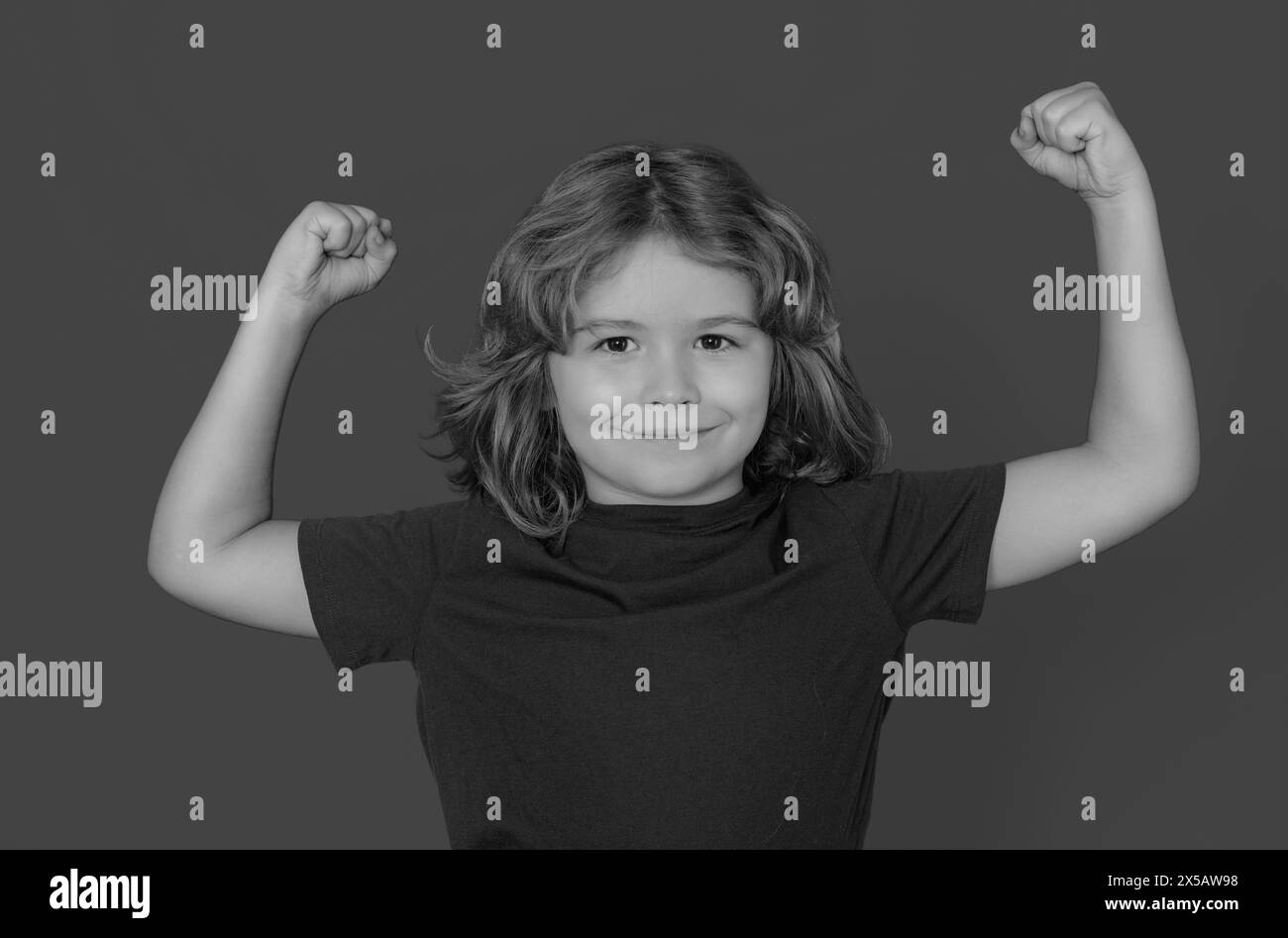 Cute child showing muscles on yellow studio isolated background. Power ...