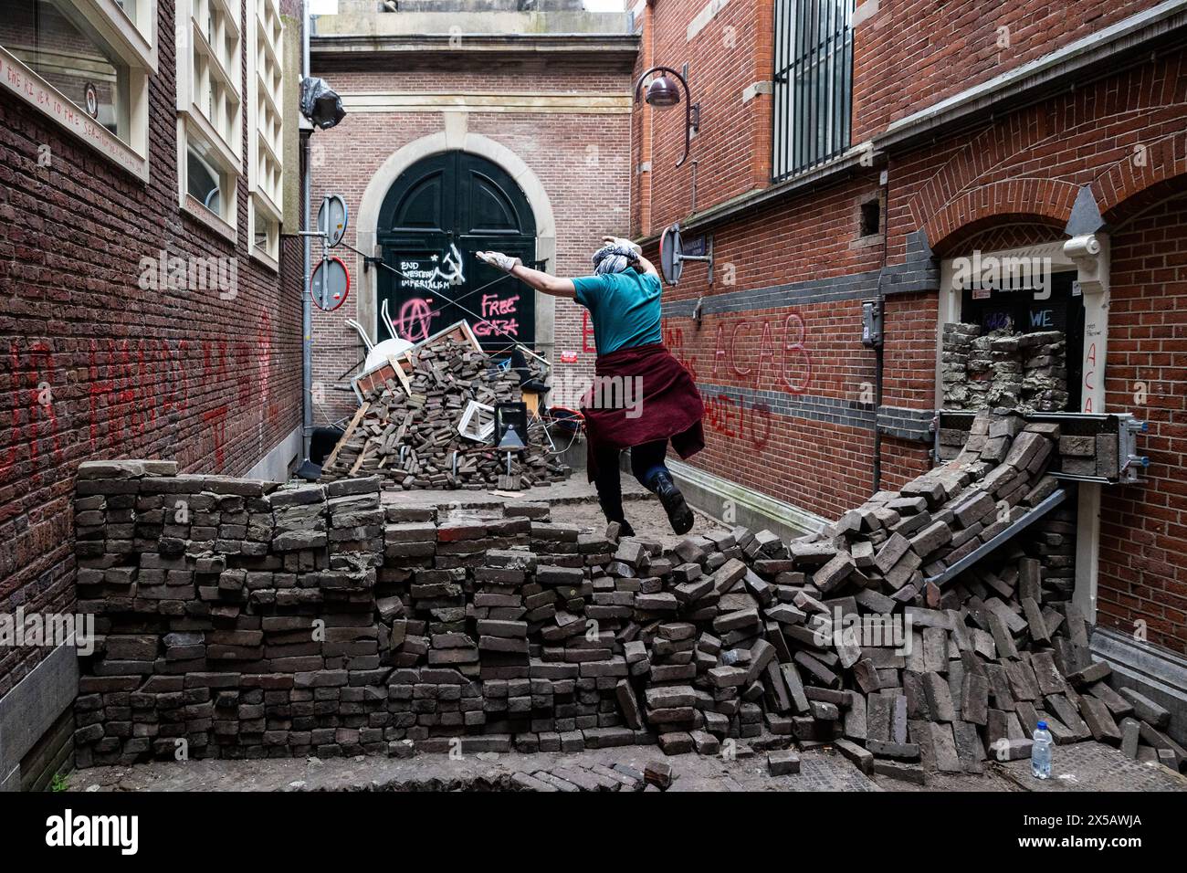AMSTERDAM - A demonstrator jumps over a barricade next to a UVA ...