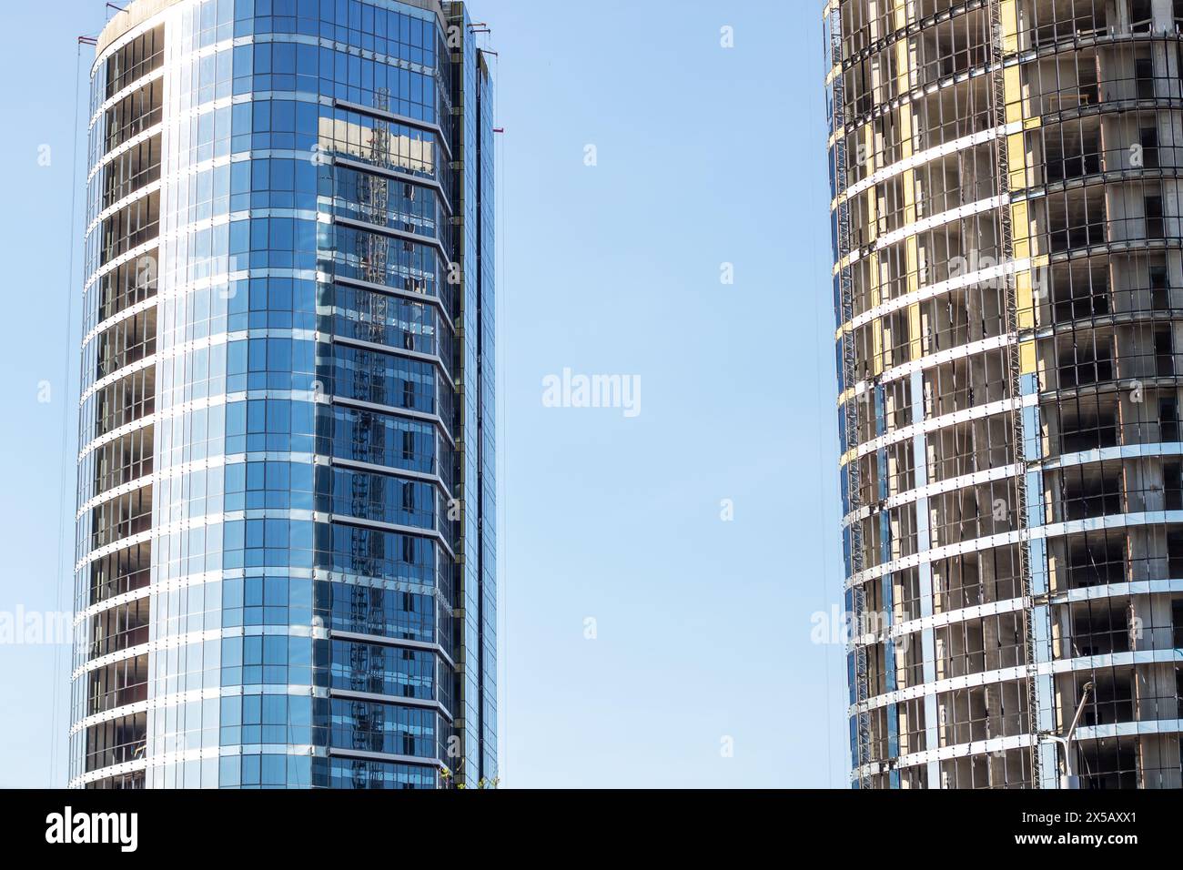 A modern skyscraper with a sleek facade stands tall against the backdrop of a clear blue sky ...