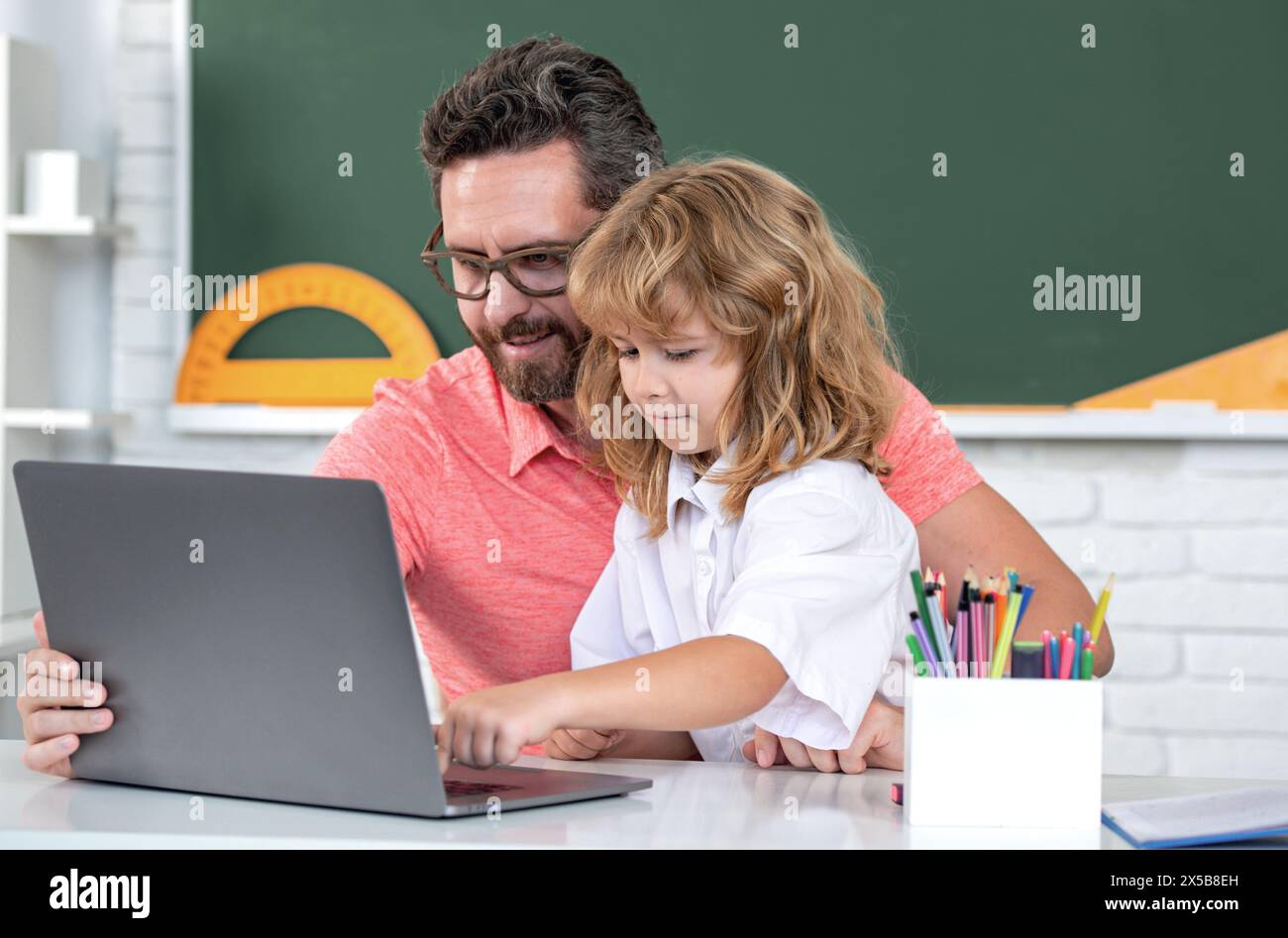 School teacher and child pupil learning at laptop computer, studying ...