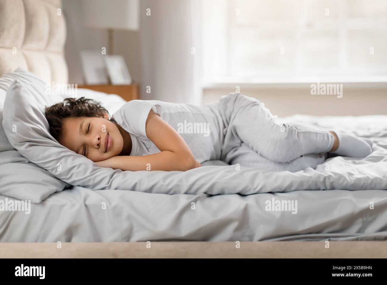 Young Boy Laying on Bed, Peacefully Sleeping Stock Photo - Alamy