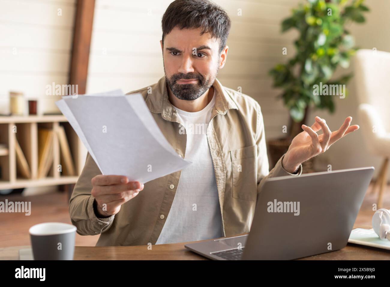 Perplexed Man Reviewing Documents at Home Office Desk During Daytime ...
