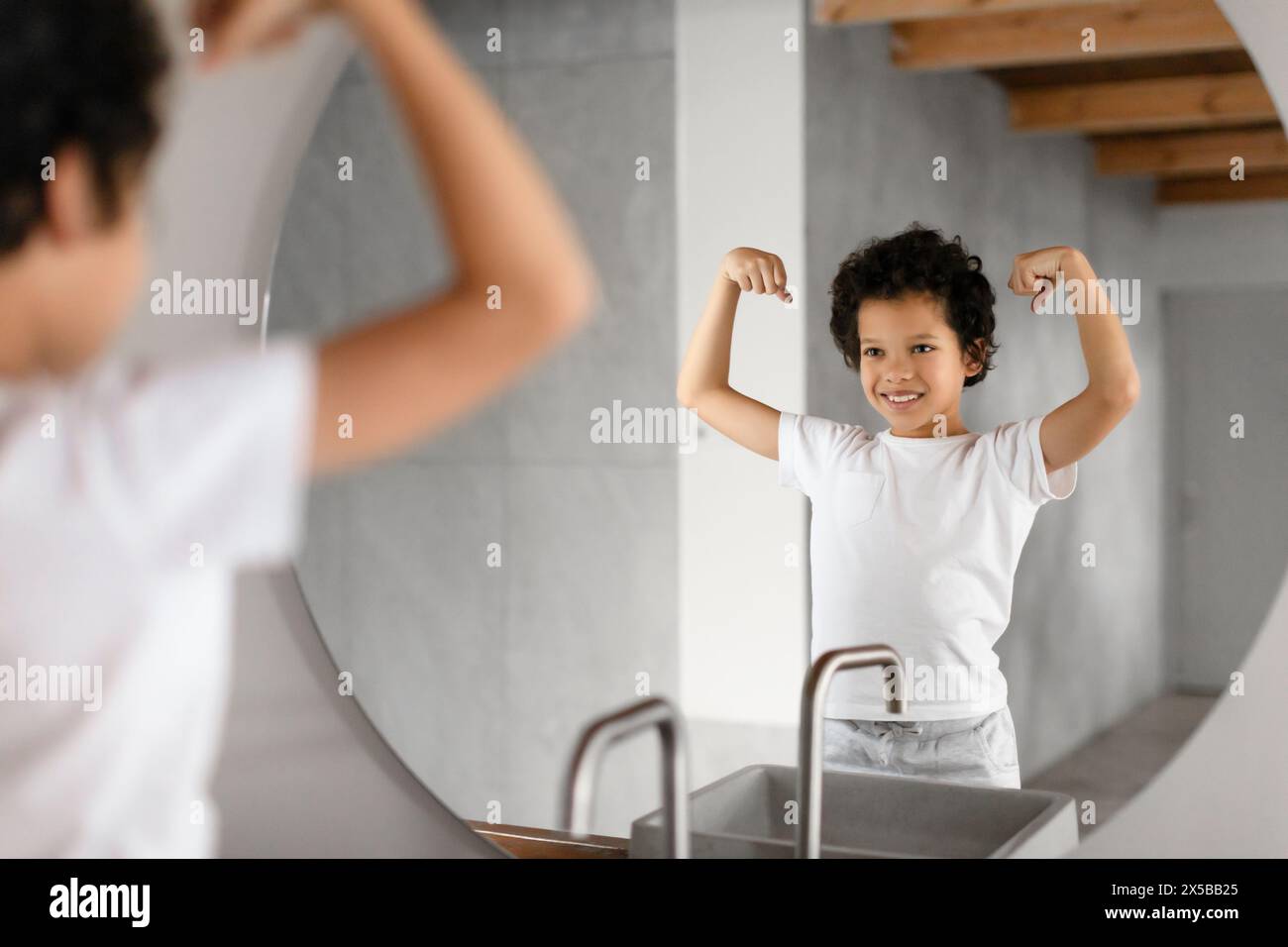 Young Child Flexing Muscles in Front of Bathroom Mirror Stock Photo - Alamy
