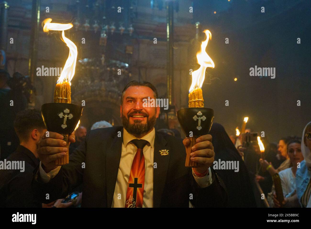 A devotee hold candles with the Holy Fire as he shows them to the ...