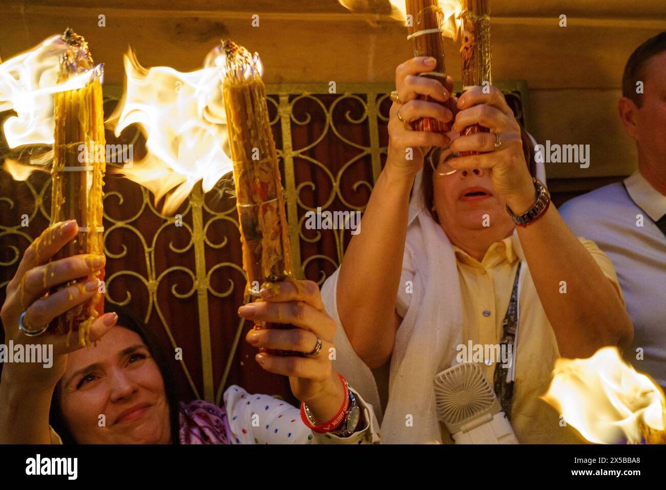 Devotees hold candles with the Holy Fire during the Holy Fire Ceremony ...