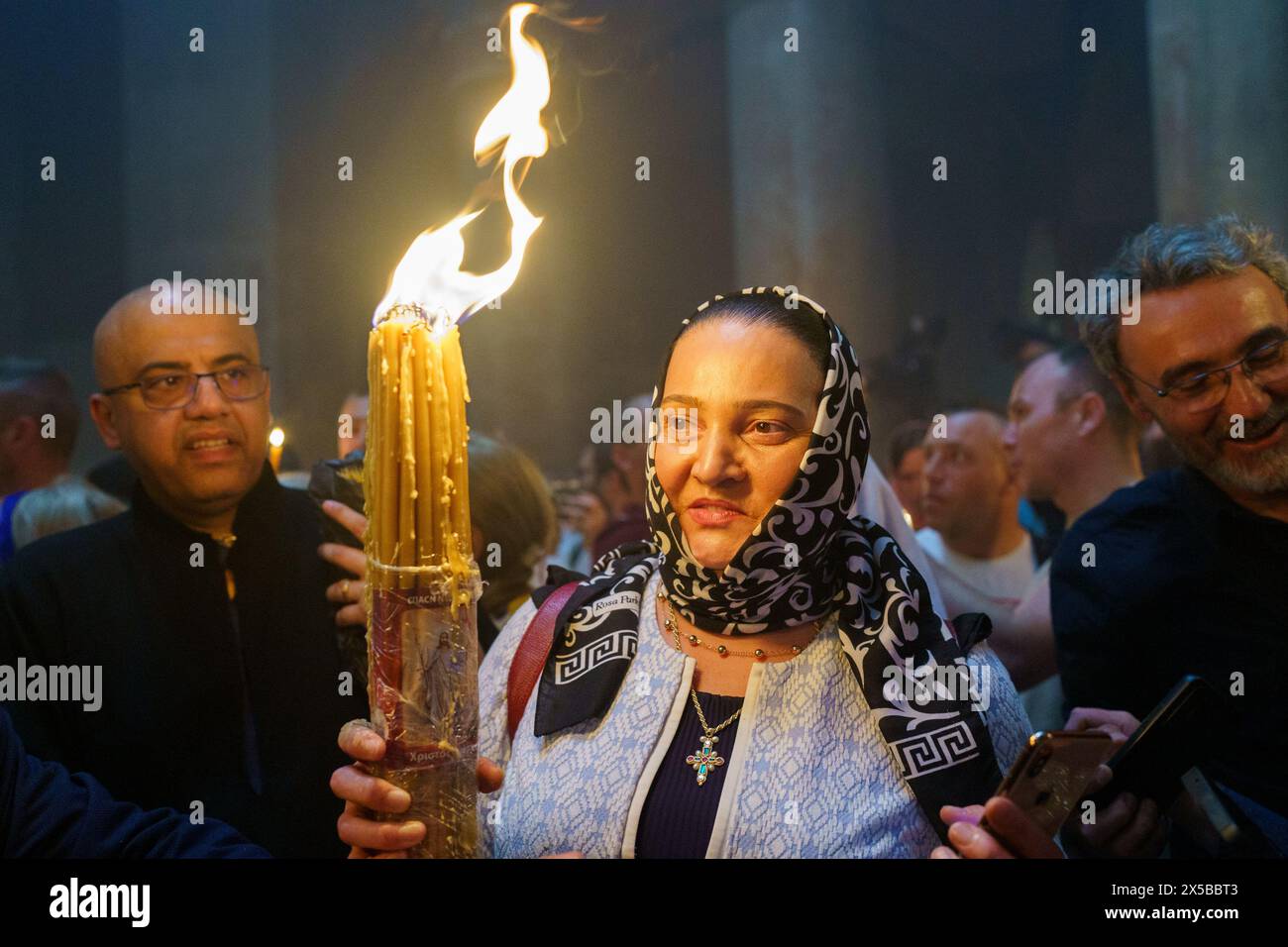 A devotee holds candles with the Holy Fire during the Holy Fire ...