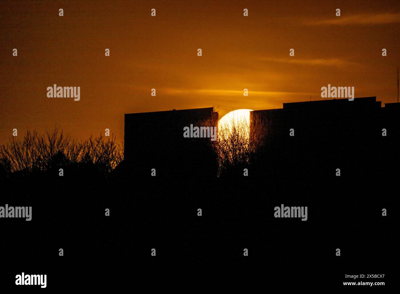 Sun setting behind large apartment buildings Stock Photo - Alamy