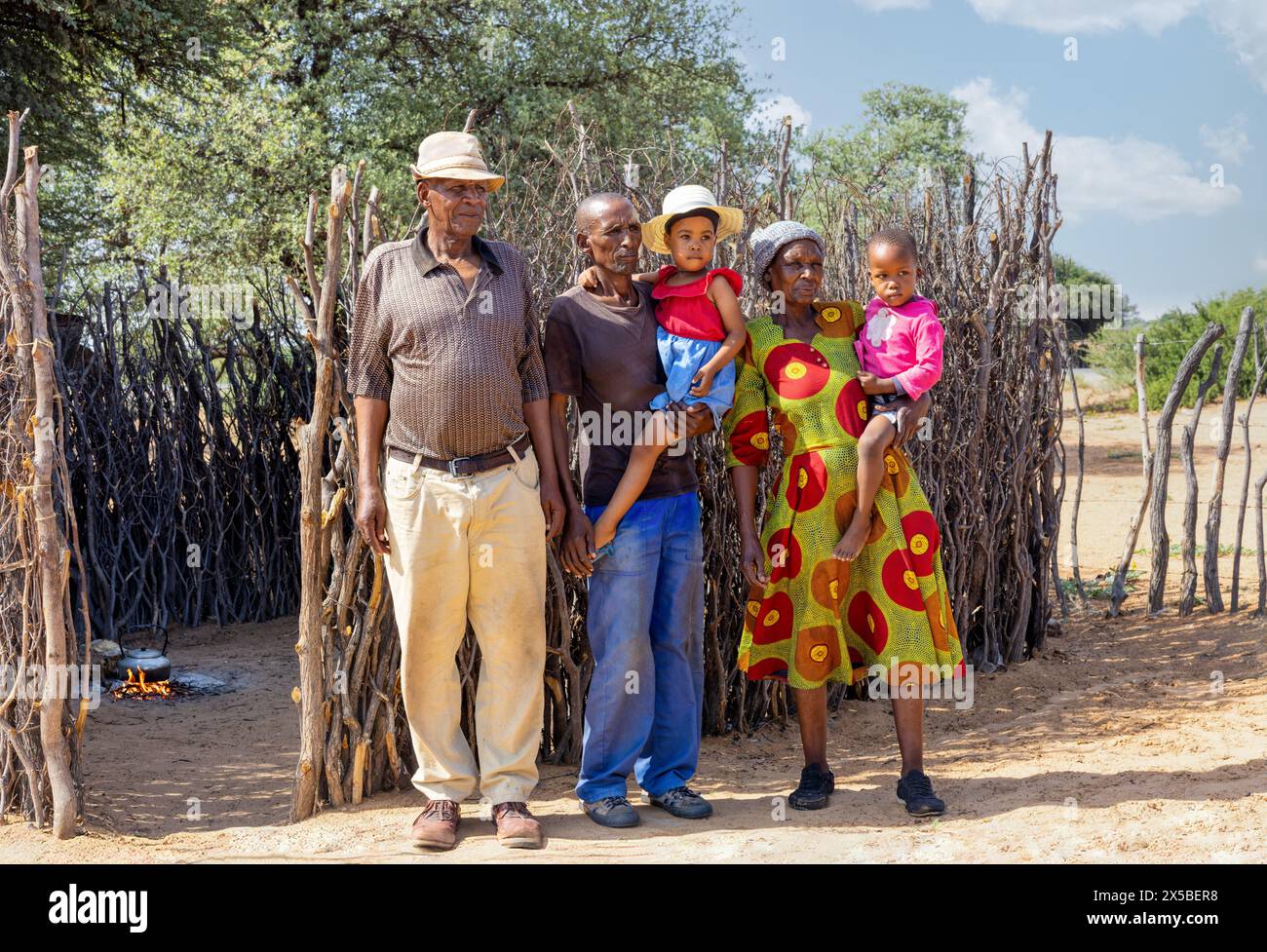 African village, large family standing in front of the outdoors kitchen ...